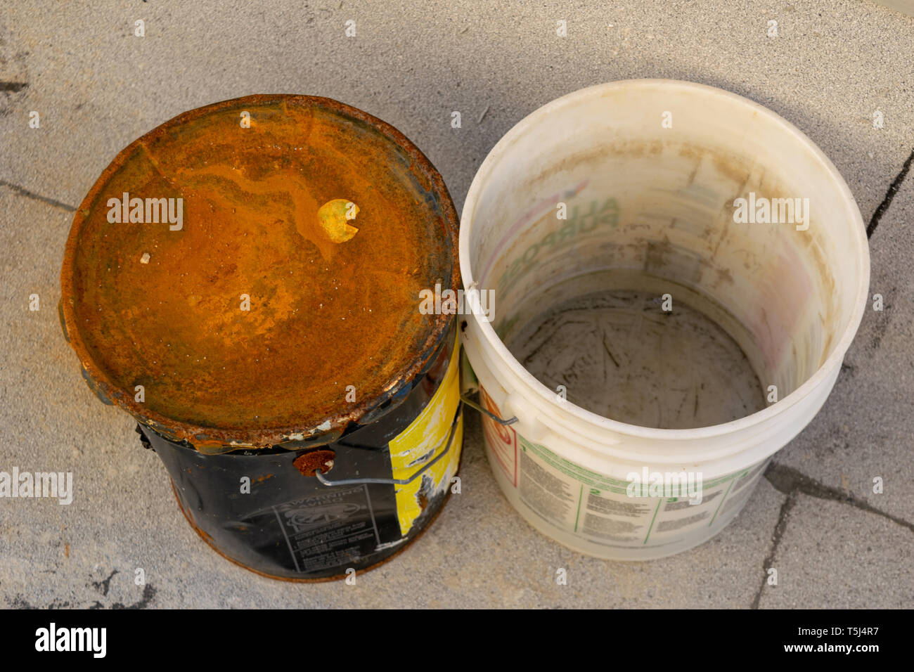 Top-down view of an old rusty metal bucket and a dirty white plastic ...