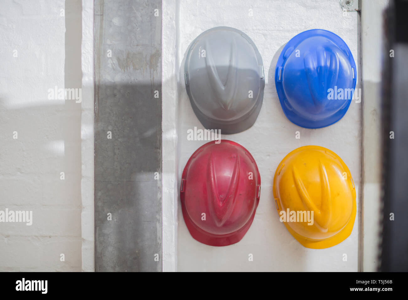 Multicolored hard hats hanging on a wall Stock Photo - Alamy