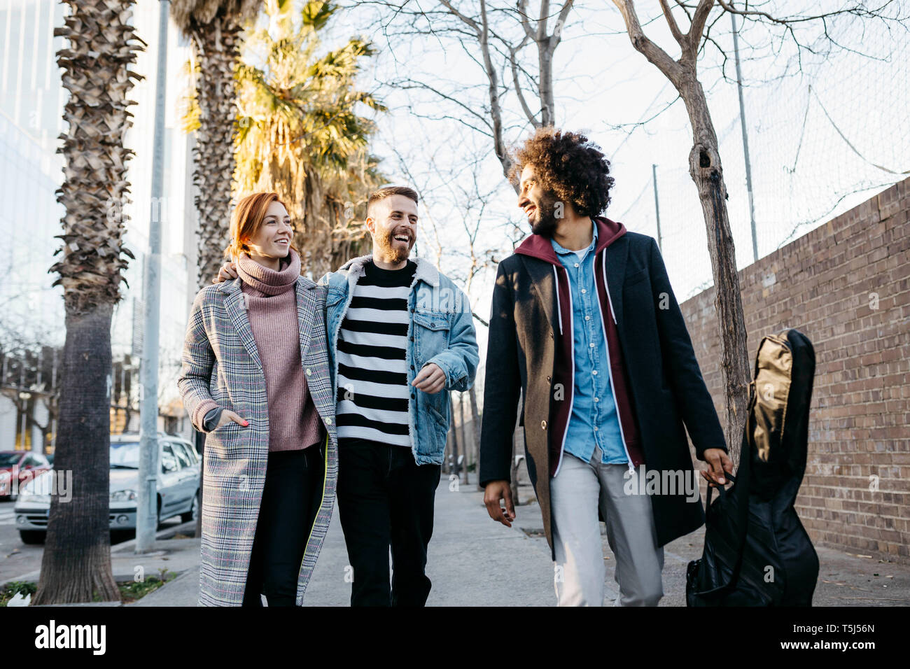 Three happy friends walking in the city Stock Photo - Alamy