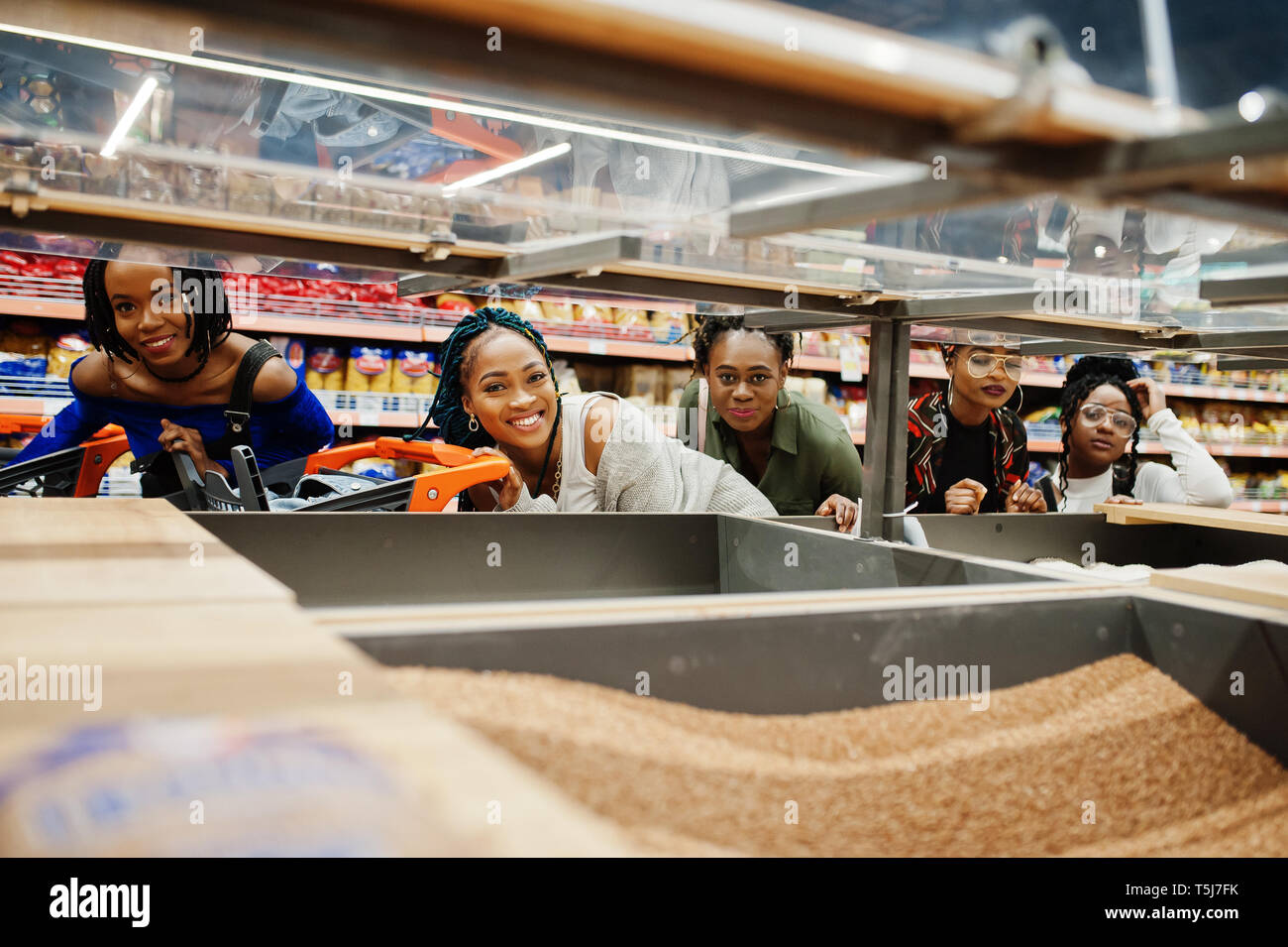 Group of five fun african womans with shopping carts choose buckwheat ...