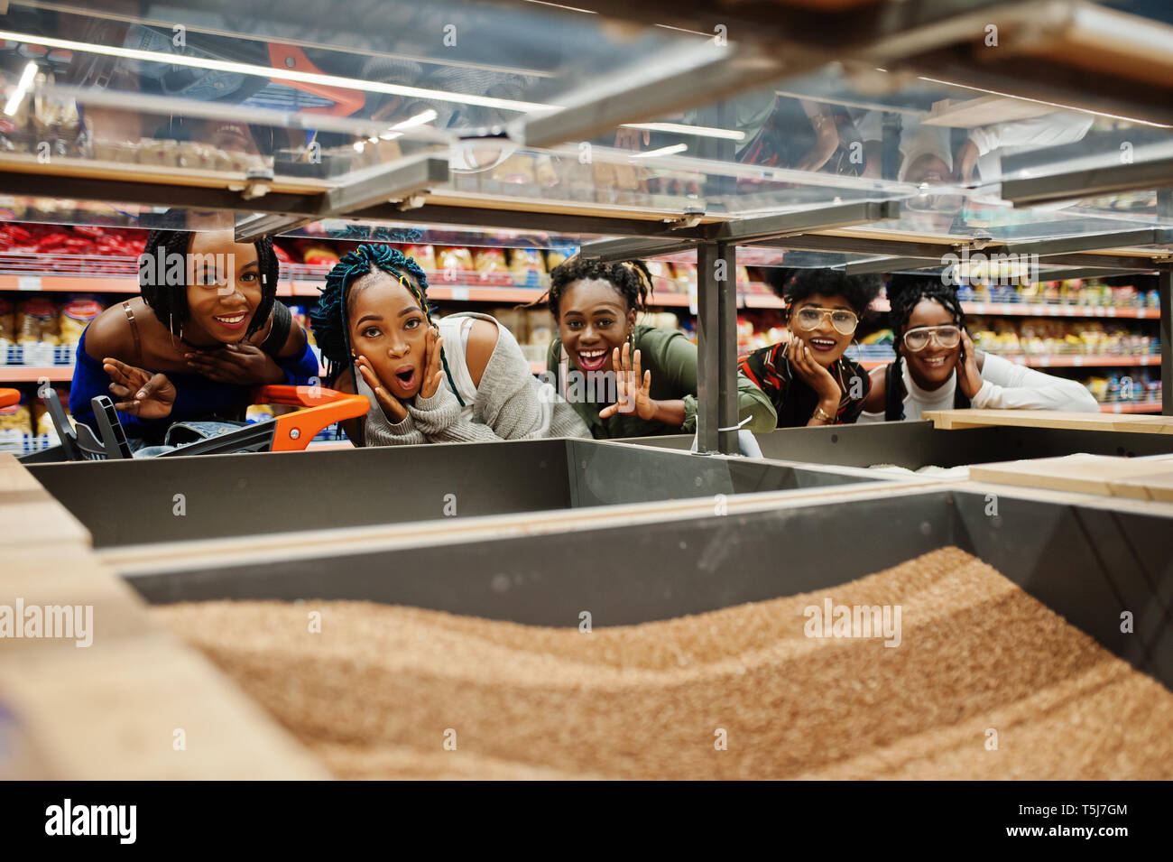 Group of five fun african womans with shopping carts choose buckwheat ...