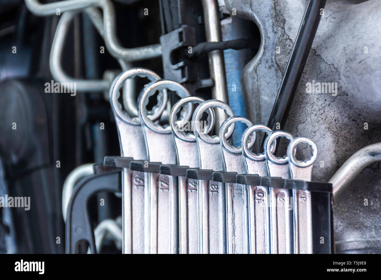 Horizontal close up view of car engine bay and specialized set of tools ...