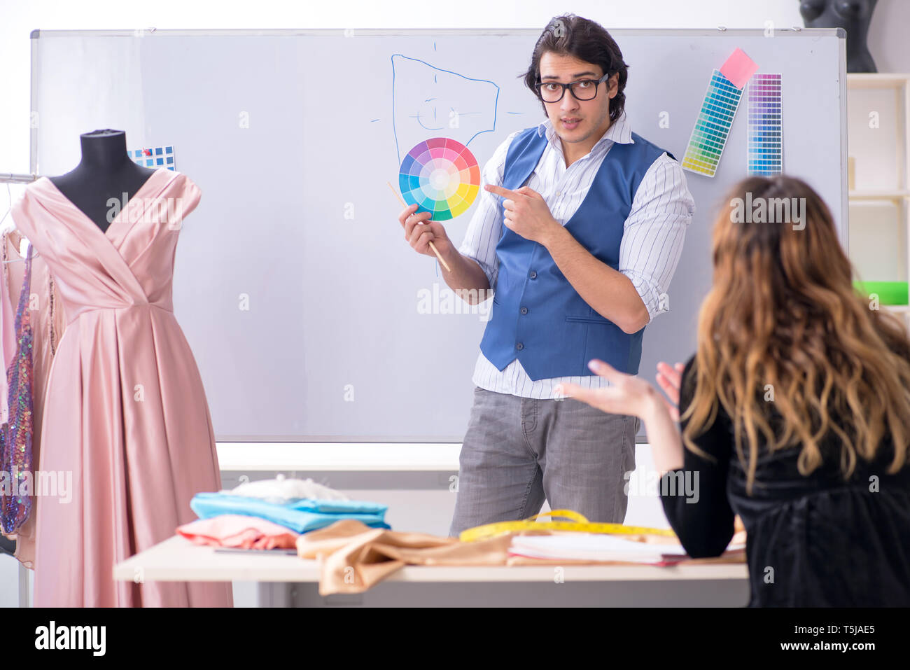 Young male tailor teaching female student Stock Photo - Alamy