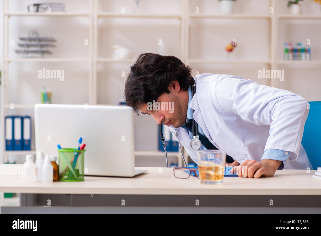 Young male doctor drinking in the office Stock Photo - Alamy