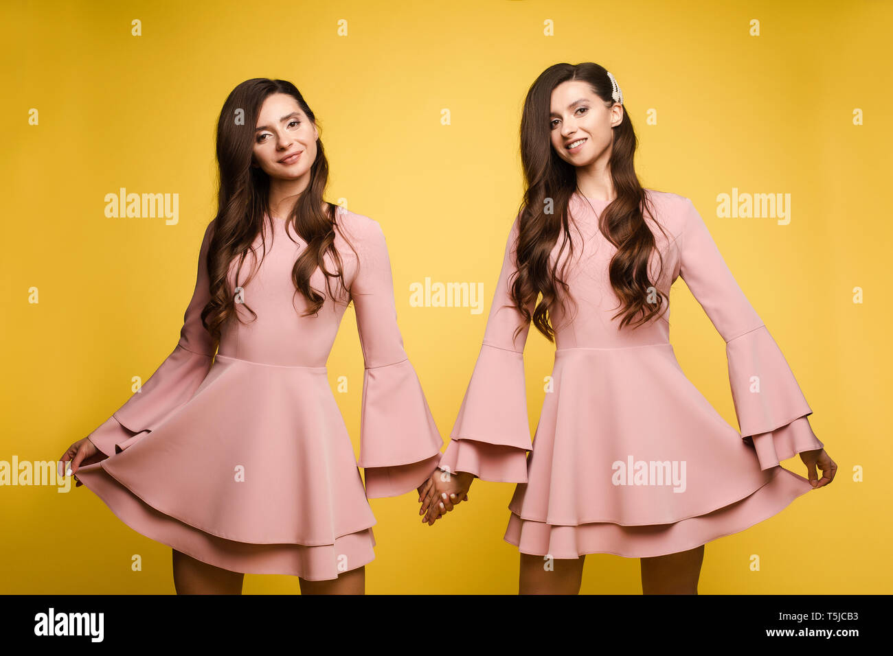 Happy sisters in pink dresses smiling and standing together Stock Photo ...