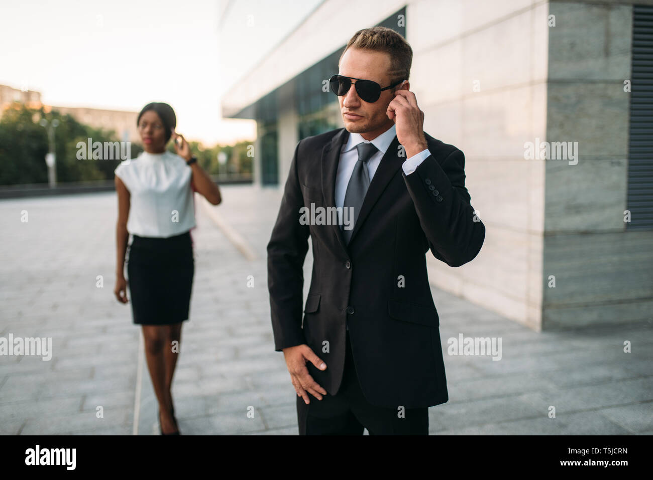 Personal bodyguard in sunglasses and black business woman. Security ...