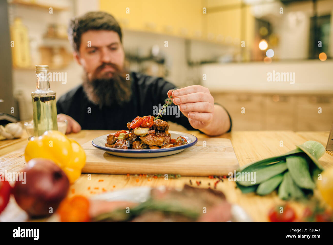 Male chef decorates with herbs a meat dish for gourmets, kitchen on ...
