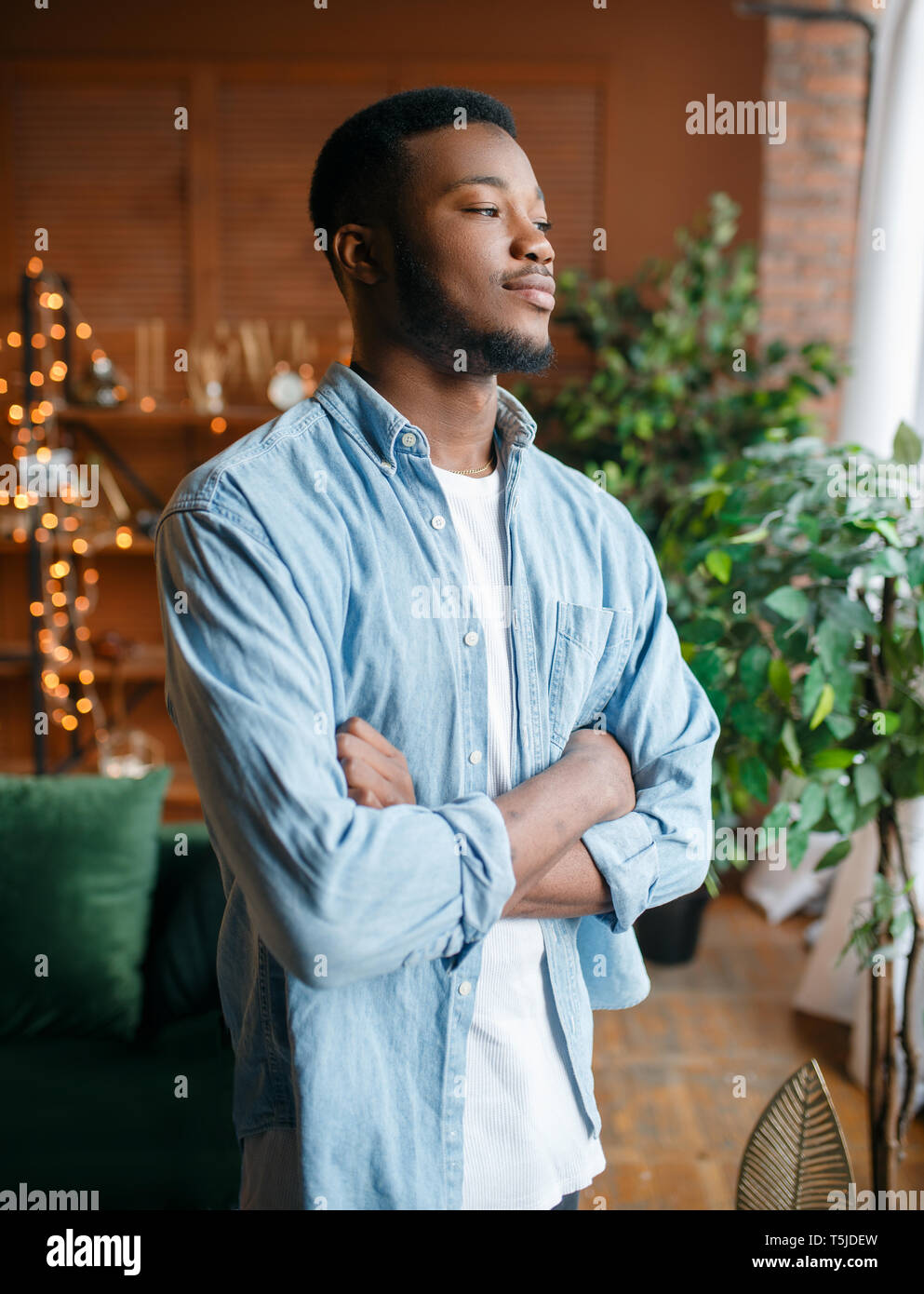 Black man with a cunning look in the living room, relaxation at home ...