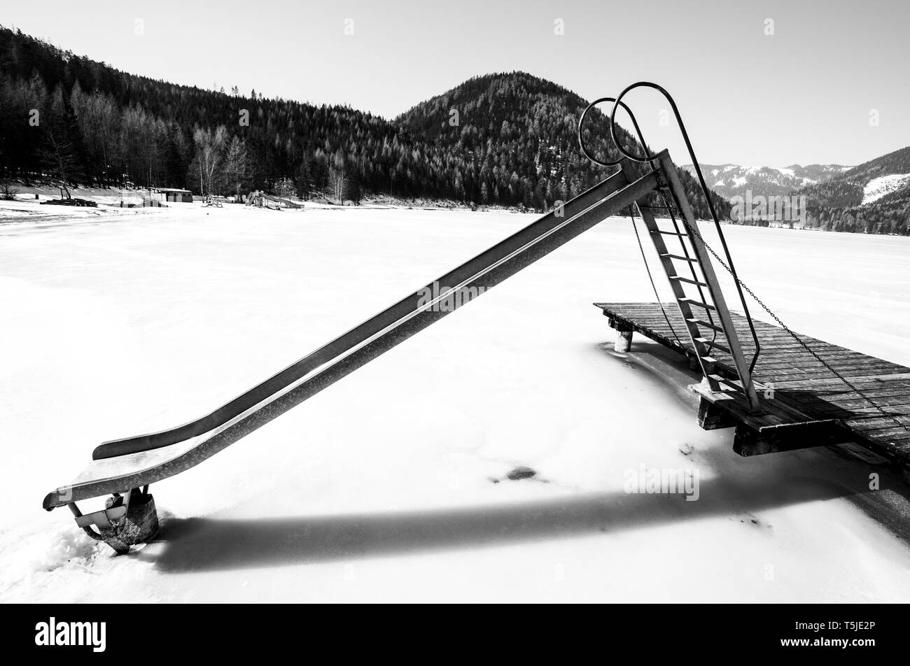 frozen lake with a waterslide covered with ice and snow in the european ...