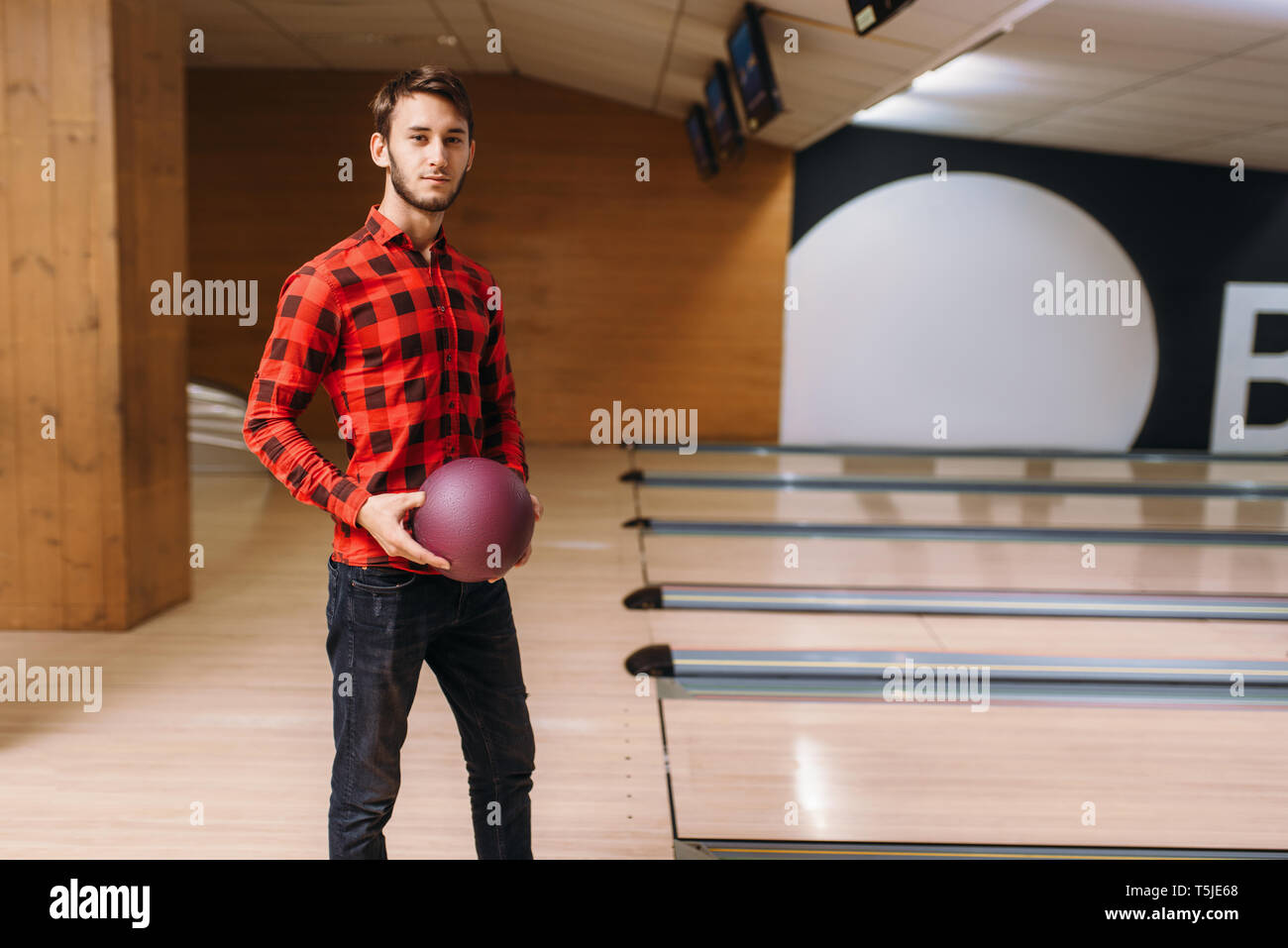 Male bowler standing on lane and holds ball in hands, back view ...