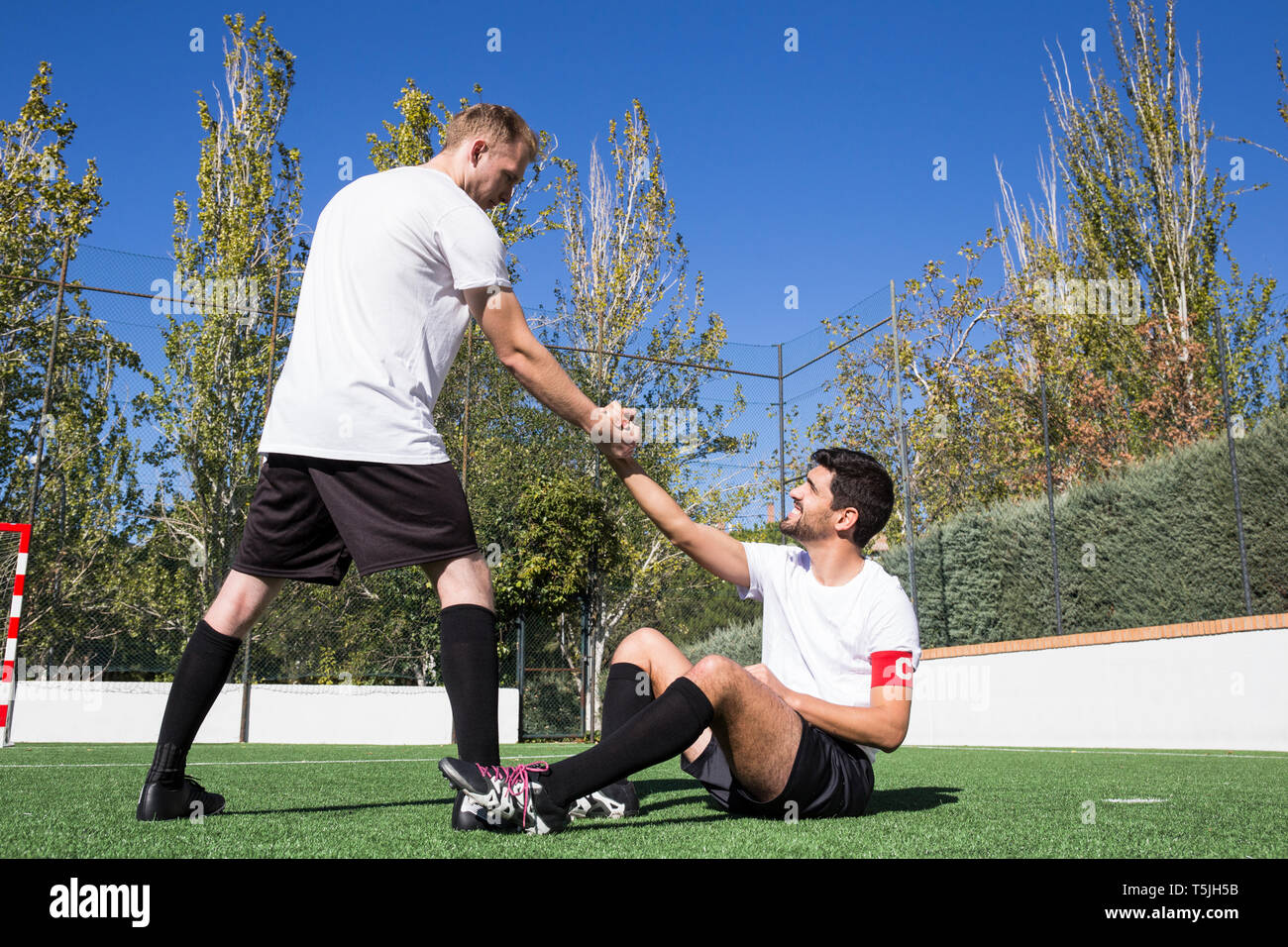 Football player helping an injured player during a match Stock Photo ...