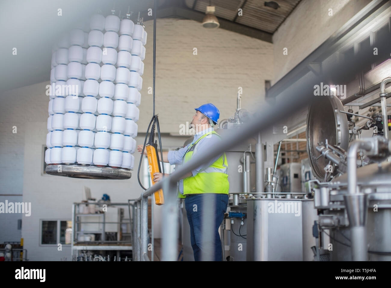 Man wearing hard hat operating control in factory Stock Photo - Alamy
