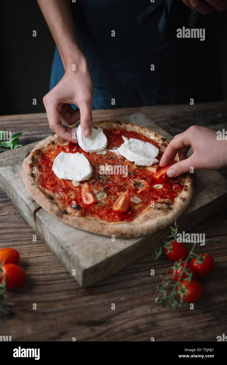 Two friends preparing a pizza with mozzarella Stock Photo - Alamy