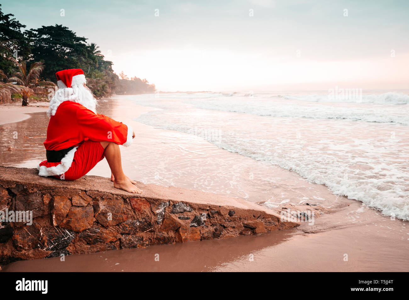 Man dressed up as santa claus sitting wall beach sunset hi-res stock ...
