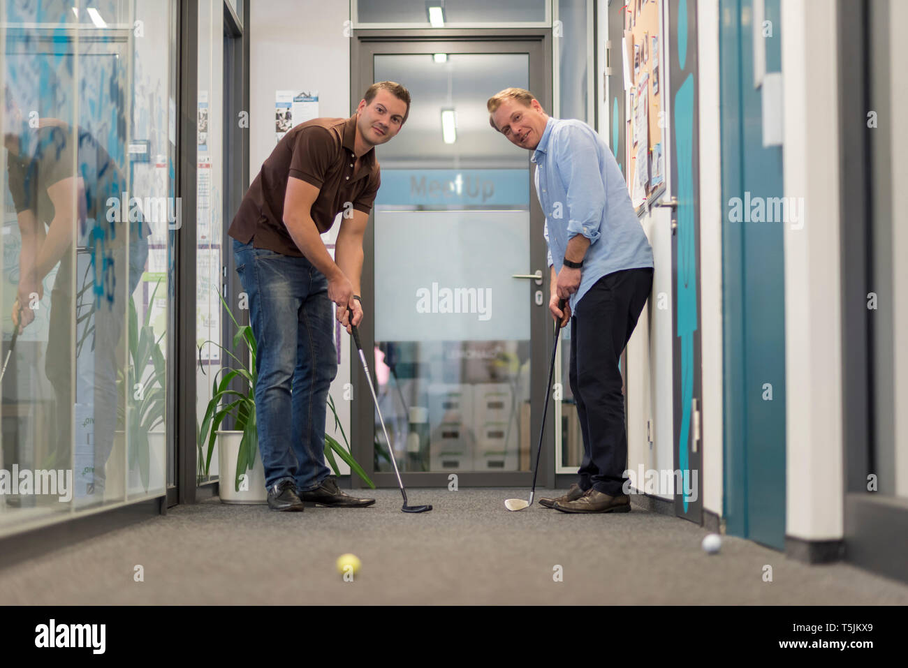 Two businessmen playing golf in office Stock Photo - Alamy