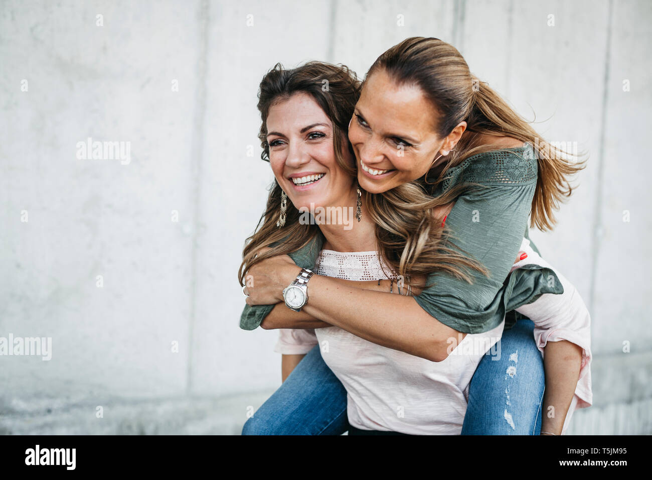 Portrait of laughing woman giving her friend a piggyback ride Stock ...