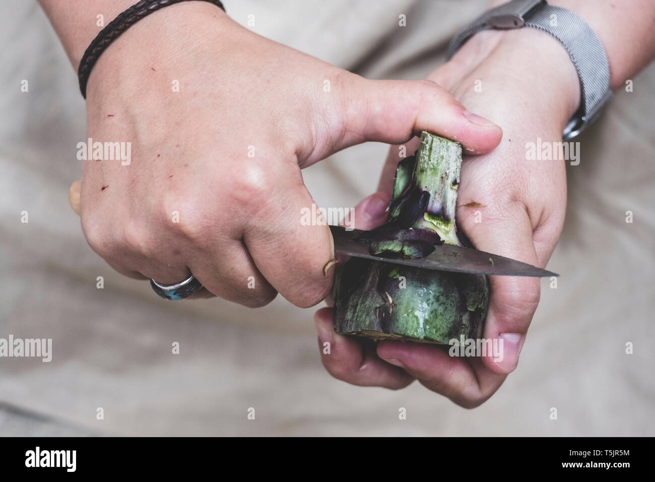 Close up of person peeling fresh artichoke with kitchen knife Stock ...