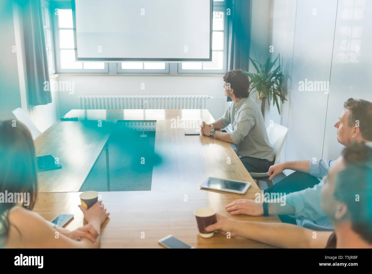 Business people sitting at conference table in office Stock Photo - Alamy