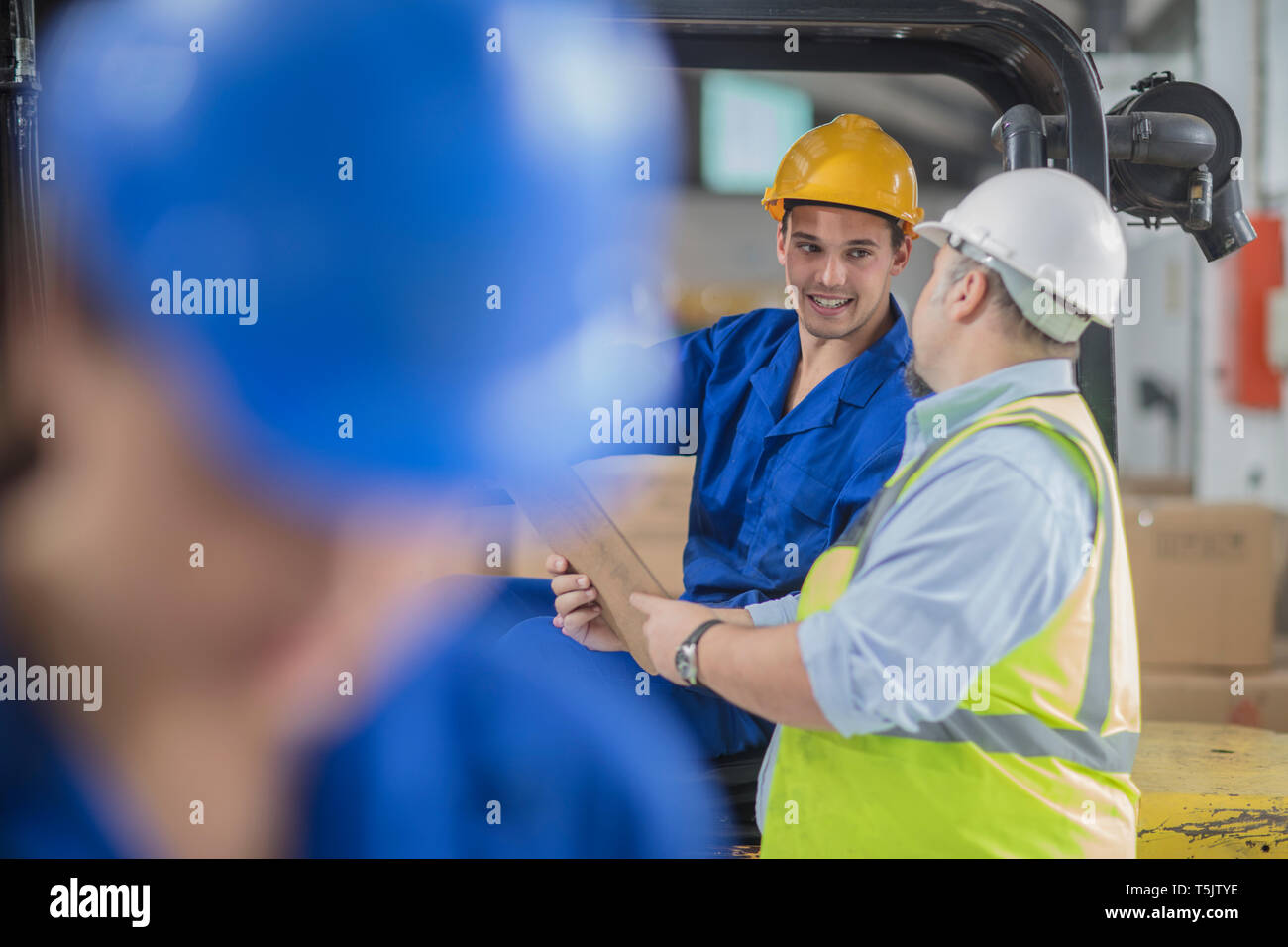 Two men wearing talking in factory Stock Photo - Alamy