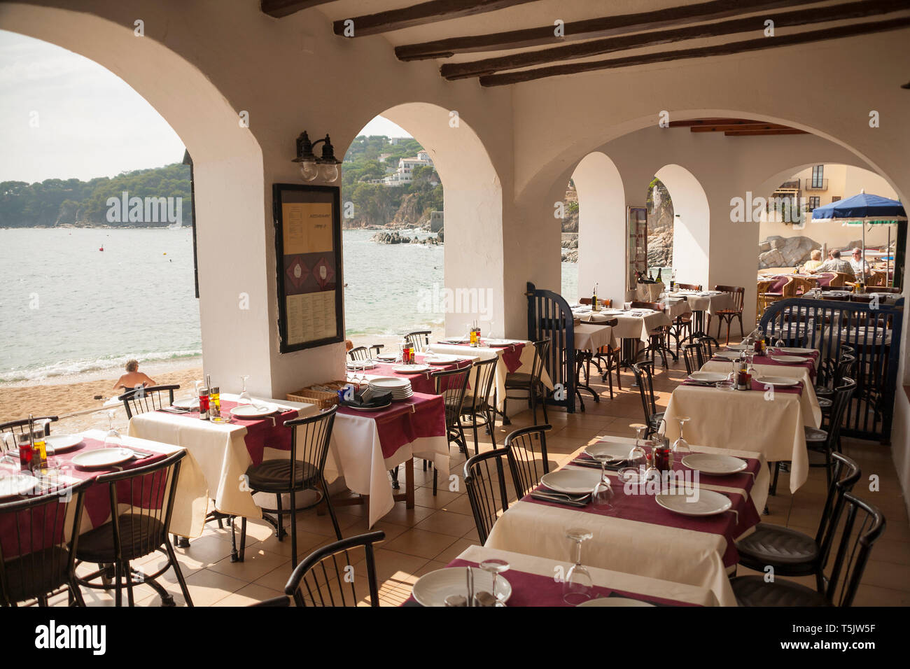 Typical Spanish seaside restaurant with tables outside under arches in ...