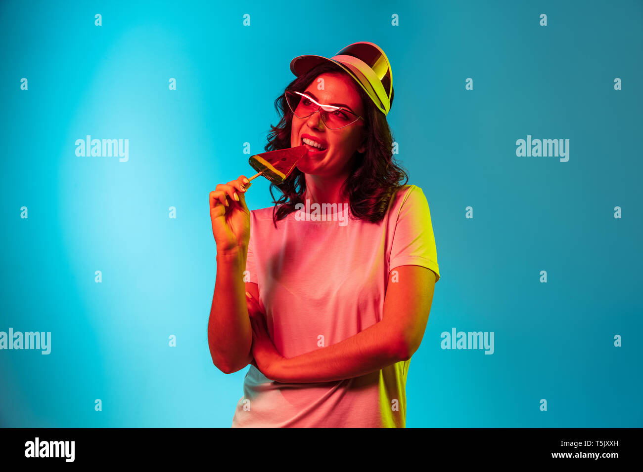 Happy young woman in sunglasses eating sweets and smiling over trendy ...