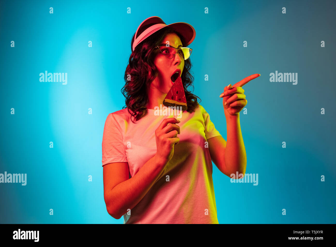 Happy young woman in sunglasses eating sweets and pointing up over ...