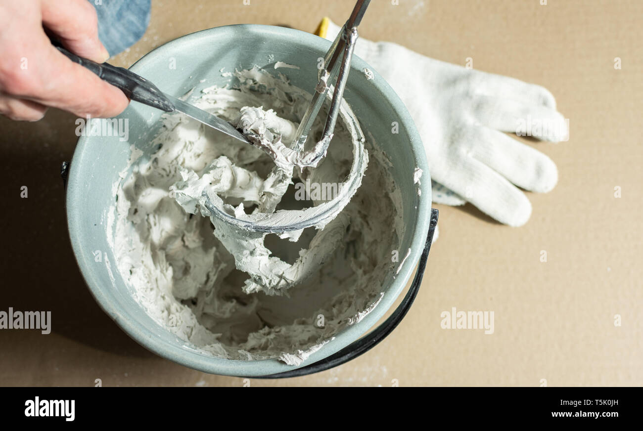 Man builder mixes gypsum putty in a bucket Stock Photo - Alamy
