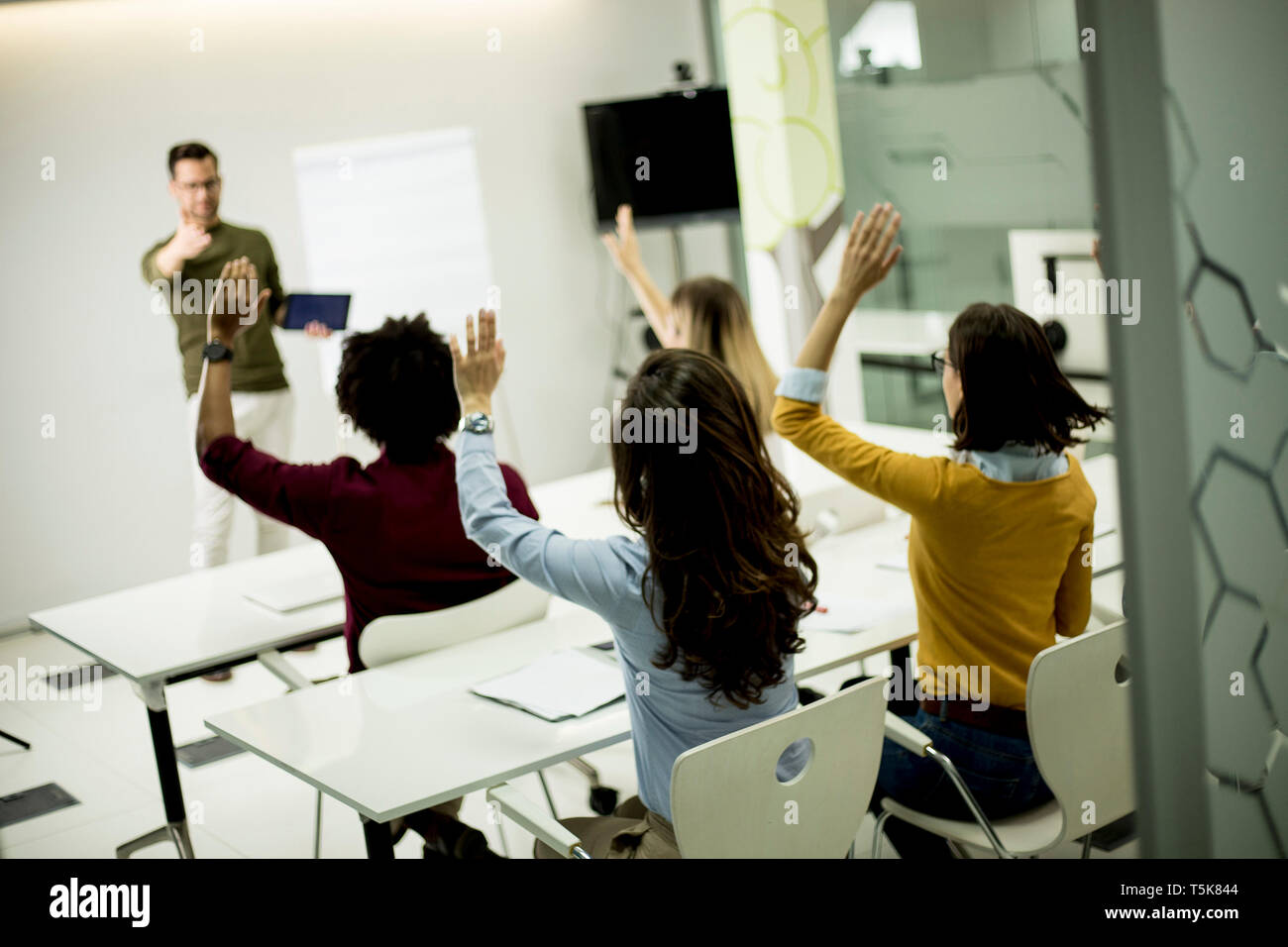 Group of young students rising hands to answer the question during the ...