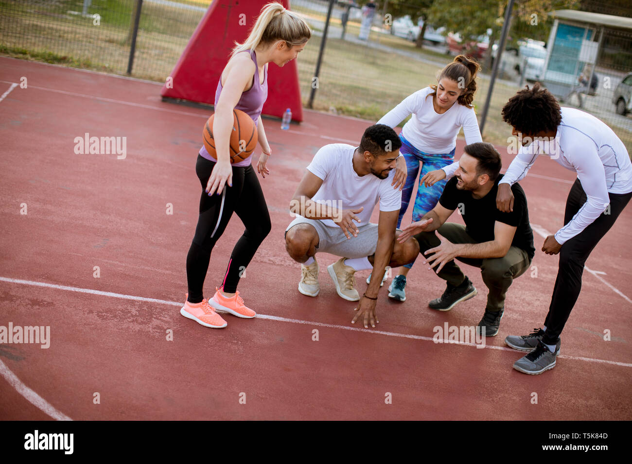 Multiethnic group of young basketball players resting on court together ...