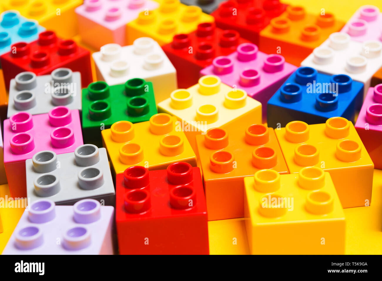 Many colorful plastic bricks of toy child constructor on yellow ...