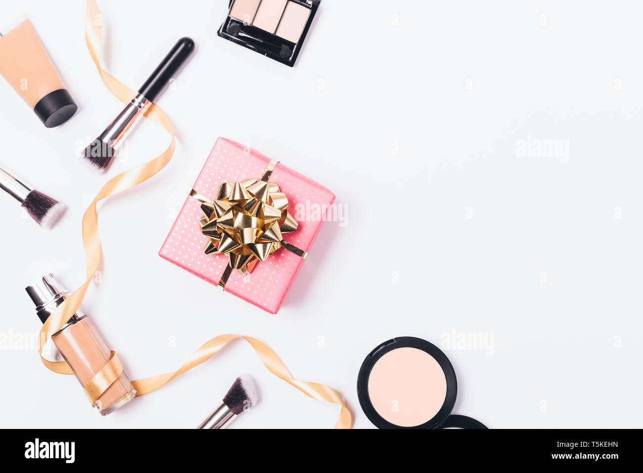 Festive flat layout of gift box and cosmetic products on white ...
