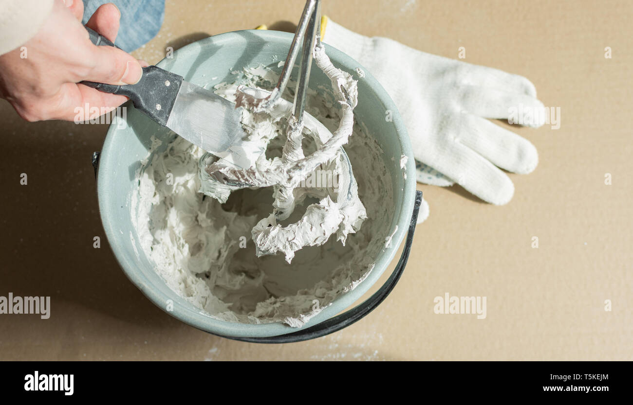 Man builder mixes gypsum putty in a bucket Stock Photo - Alamy