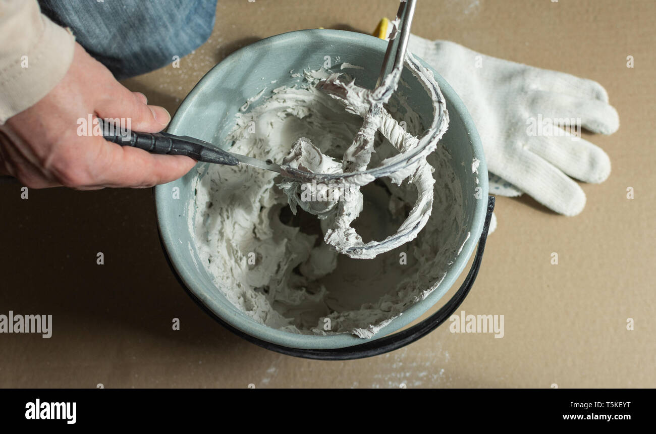 Man builder mixes gypsum putty in a bucket Stock Photo - Alamy