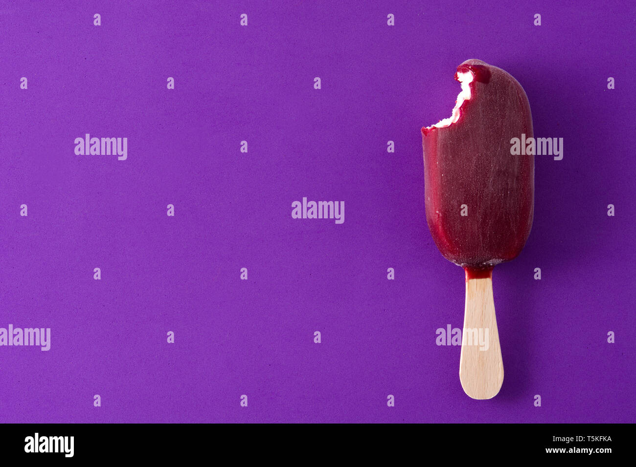 Bitten strawberry popsicle on violet background. Top view. Copyspace ...