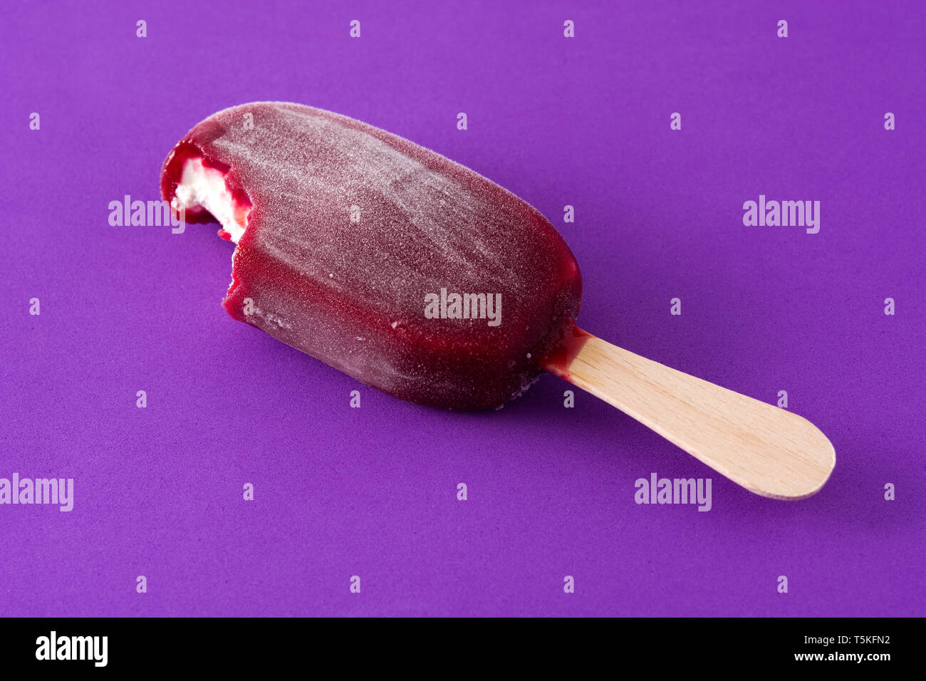 Bitten strawberry popsicle on violet background Stock Photo - Alamy