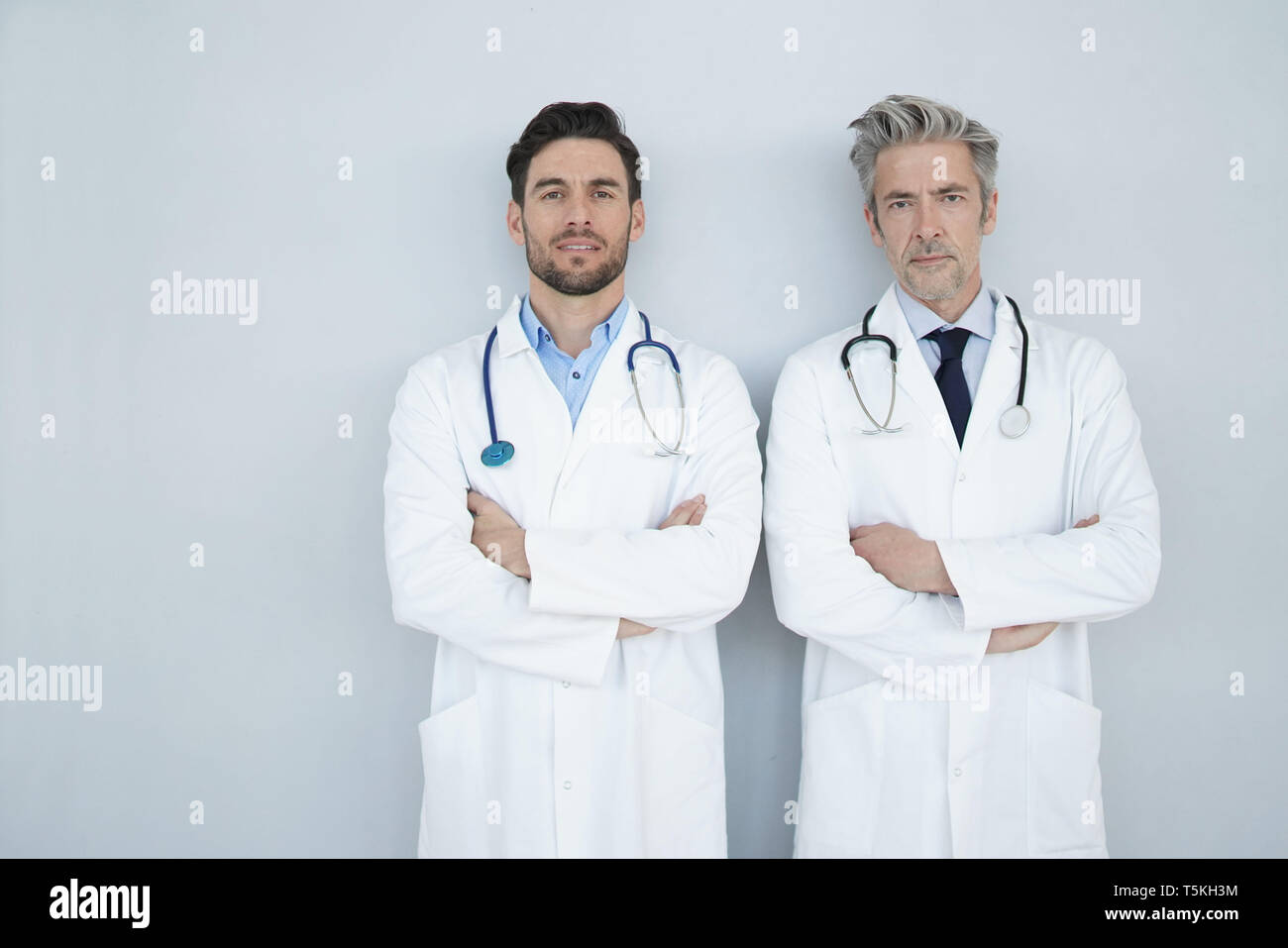 Two doctors looking at camera on grey background Stock Photo - Alamy