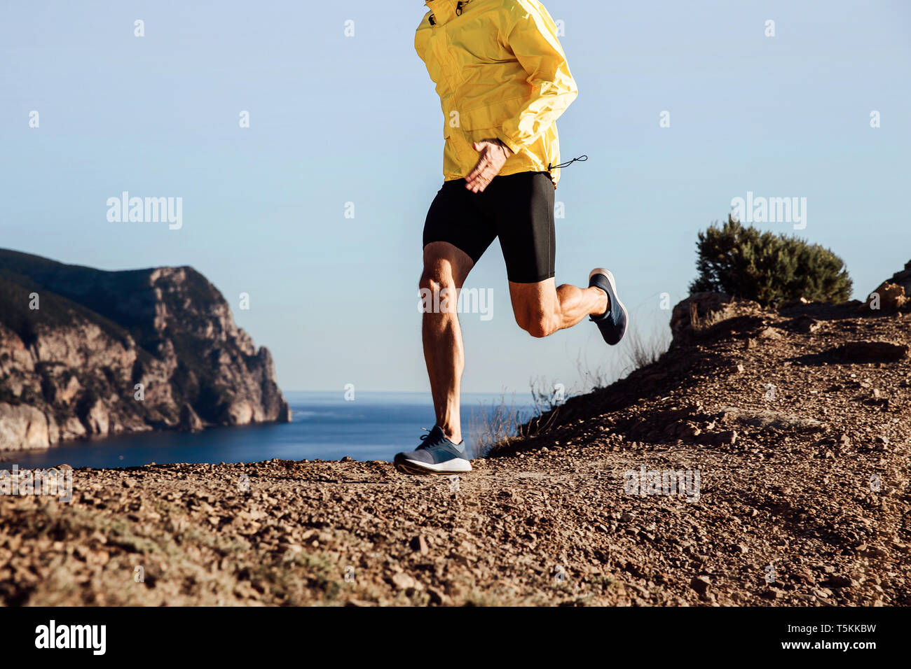 male runner running mountain trail in yellow jacket Stock Photo - Alamy