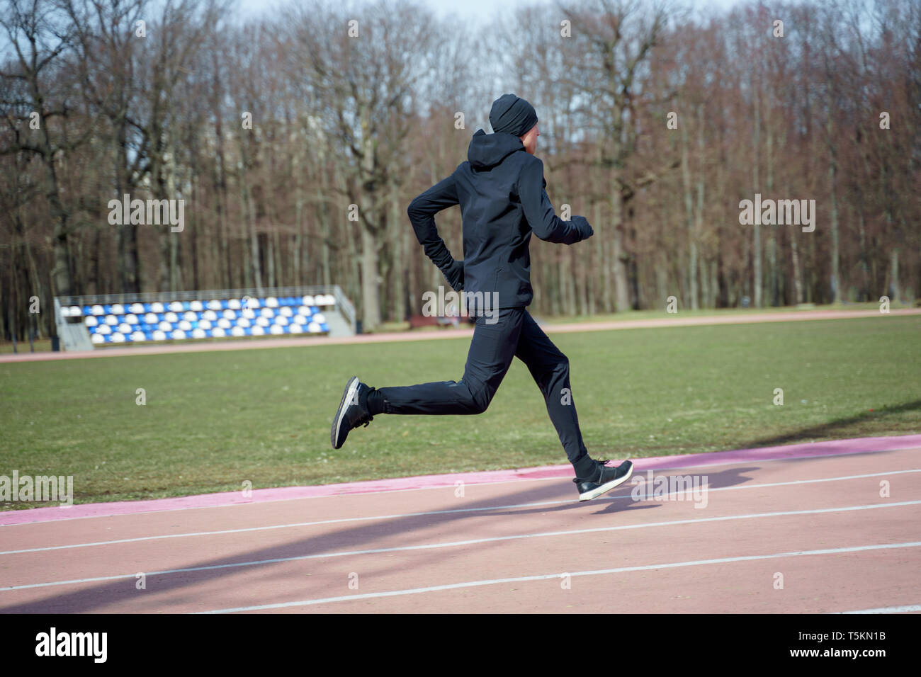 Photo on side of sports man running through stadium during spring jog ...