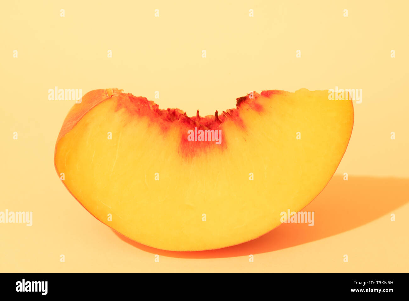 Juicy slice of peach, vivid colored on yellow background Stock Photo ...