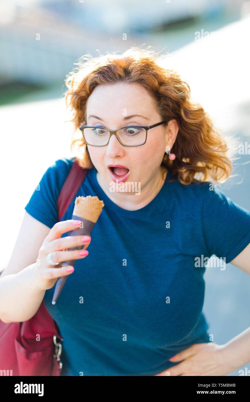 Surprised woman in blue T-shirt looking on ice cream cone - emotional ...