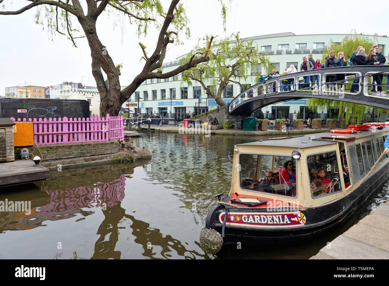 The Regents Canal with tourists on a narrow boat, Camden Town market, North London England UK ...