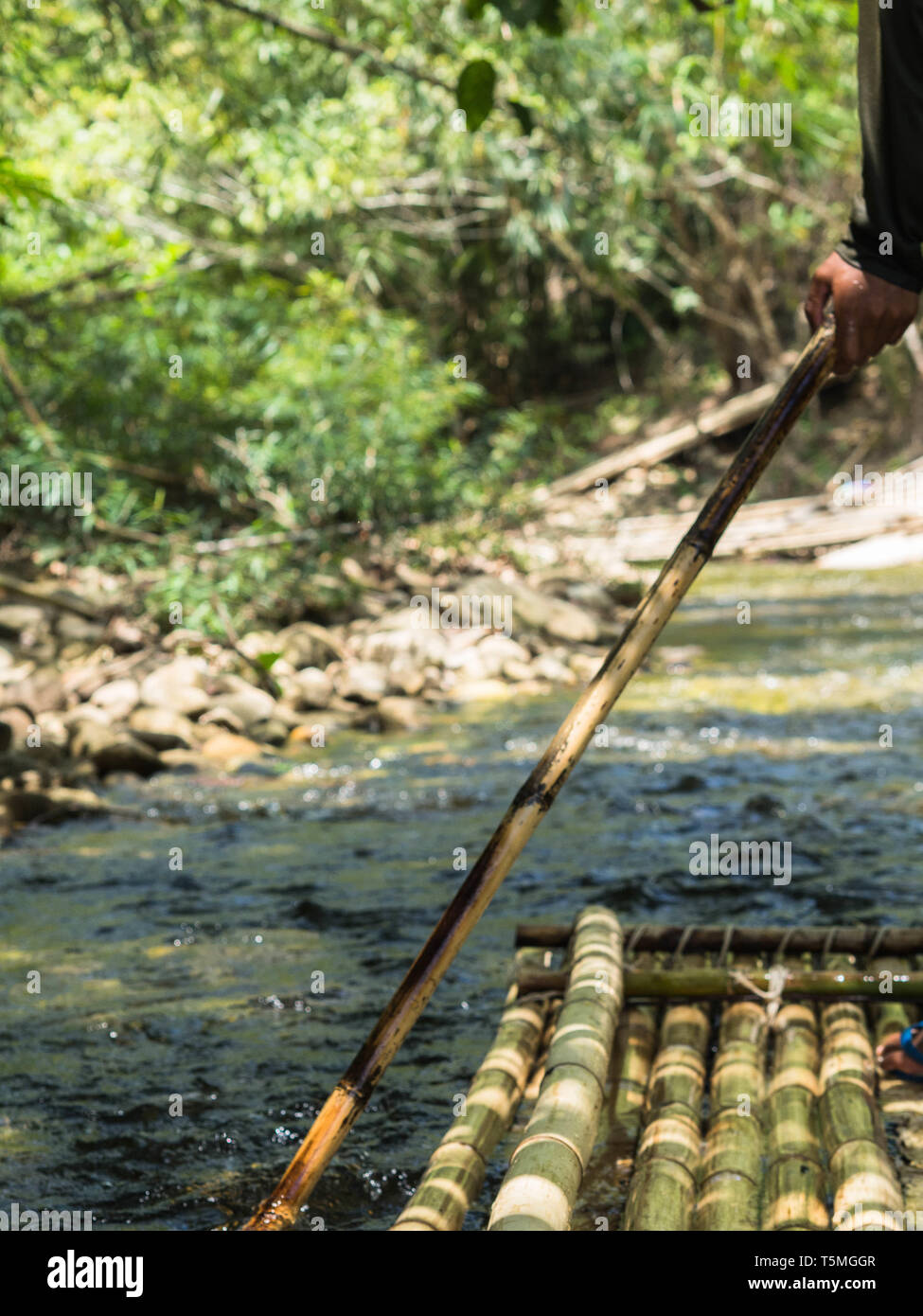 Undefined man drives a makeshift raft sailing along a river in the ...