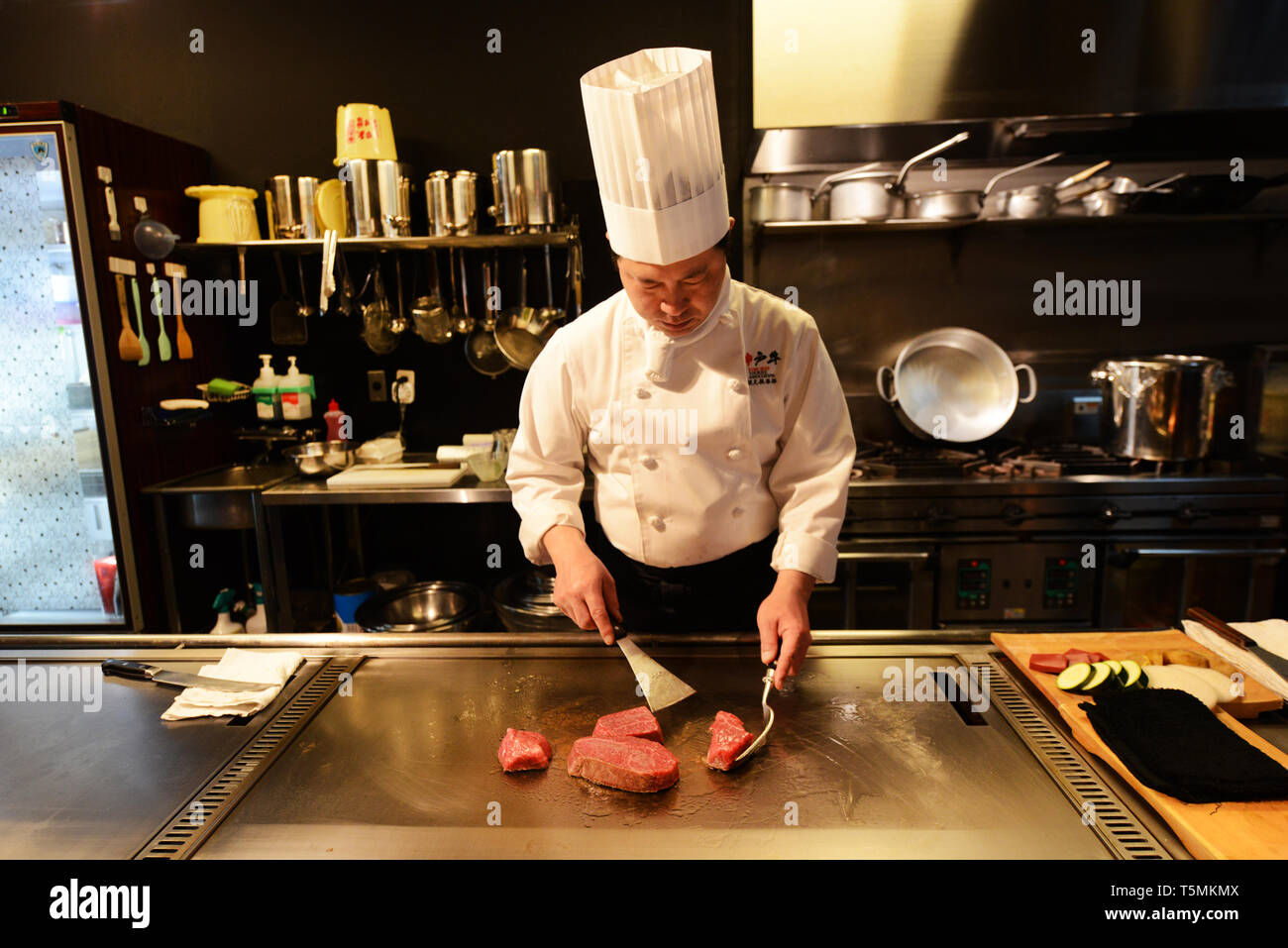A Japanese Teppanyaki chef grilling Kobe beef steaks in a traditional ...