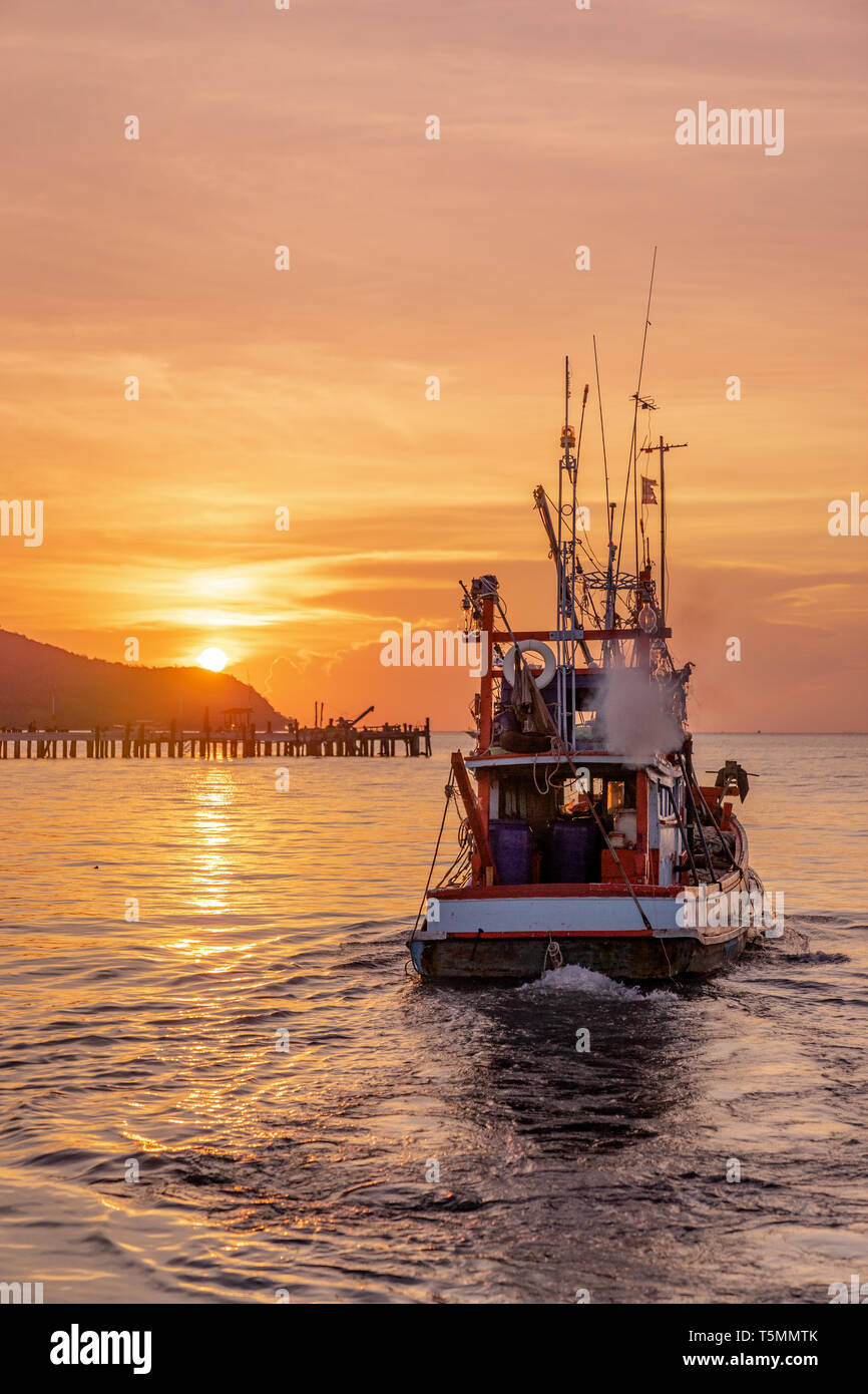 low light fisherman boat floating on sea during golden sunset Stock ...