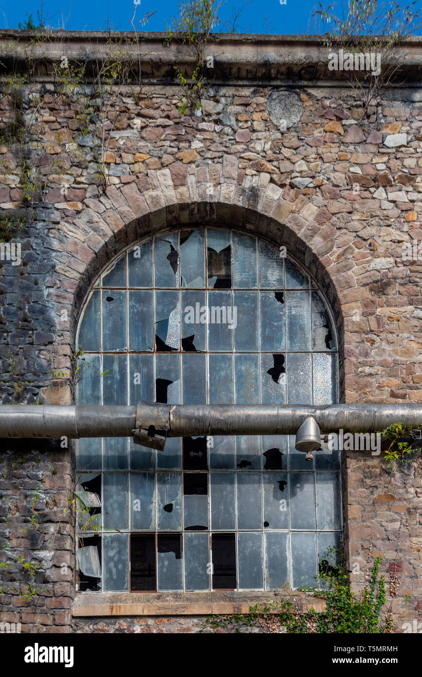 Urban industrial decay. A large broken factory window set in brick work ...