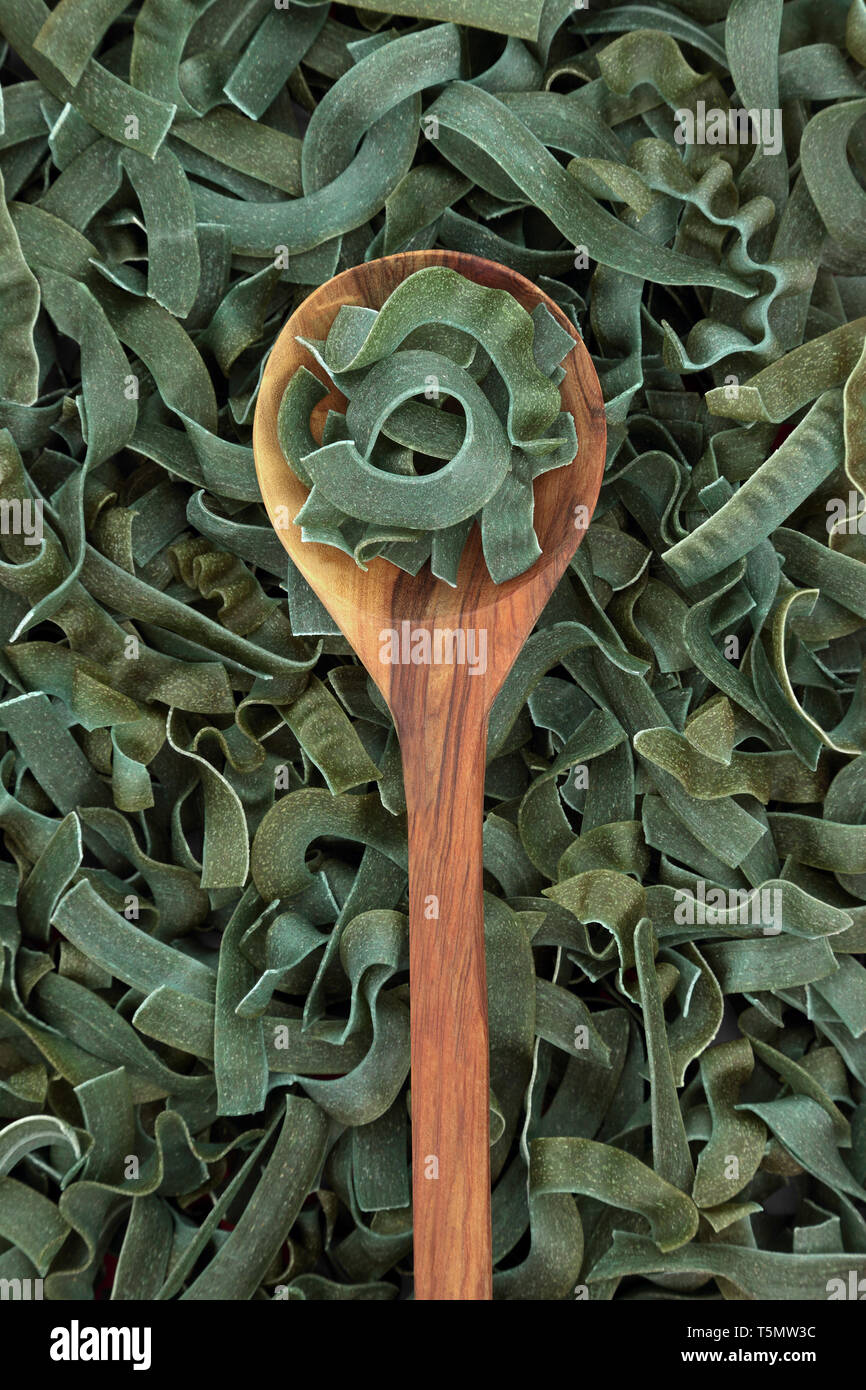 Sprouted spelt spirulina tagliatelle pasta on an olive wood spoon and ...