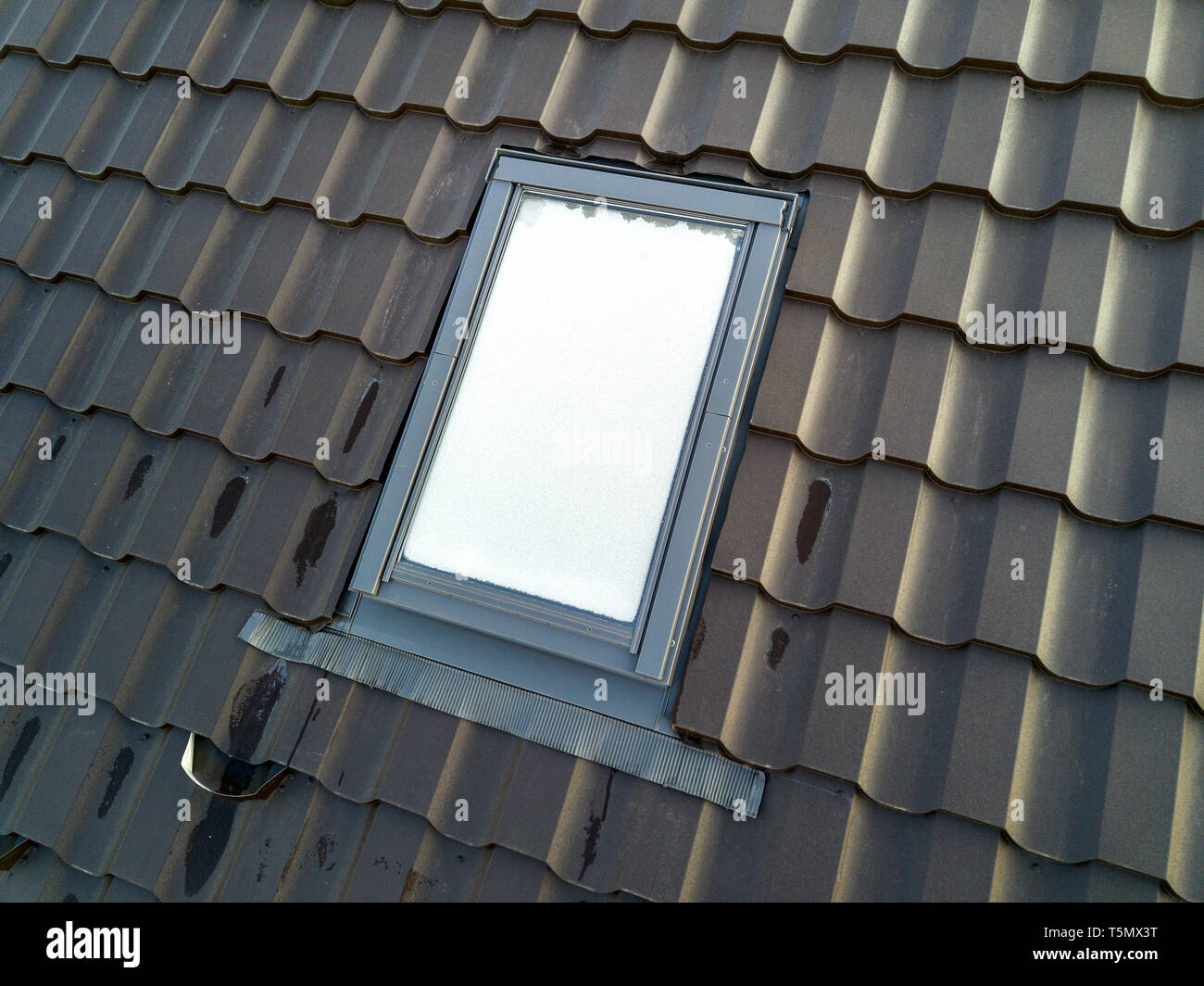 Close-up of new attic plastic window installed in shingled house roof ...