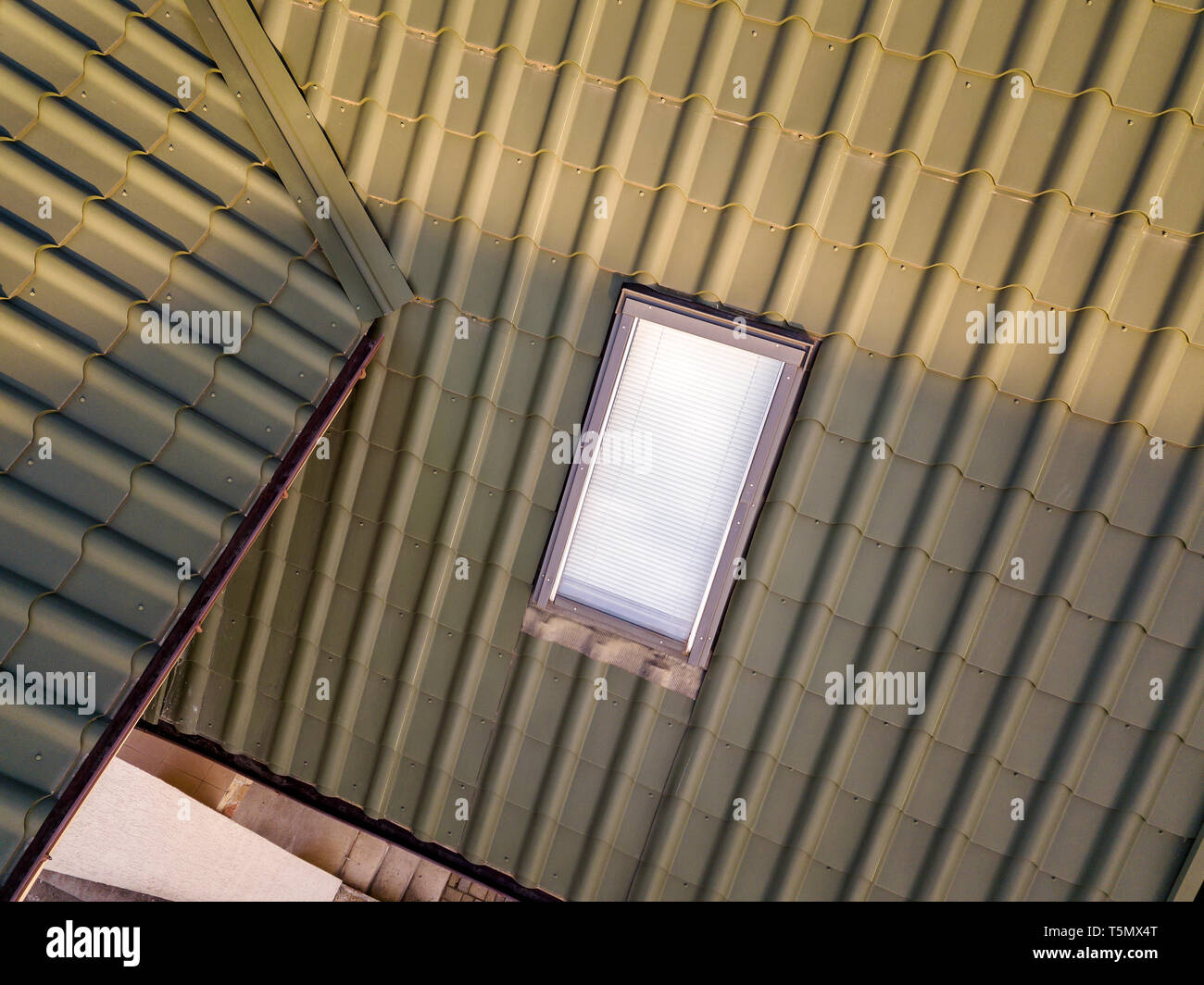Close-up of new attic plastic window installed in shingled house roof ...