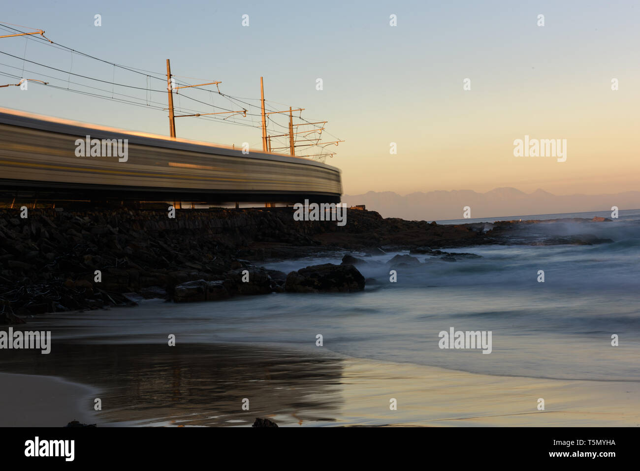 A Metro train travels the Simons Town to Muizenberg track that follows ...