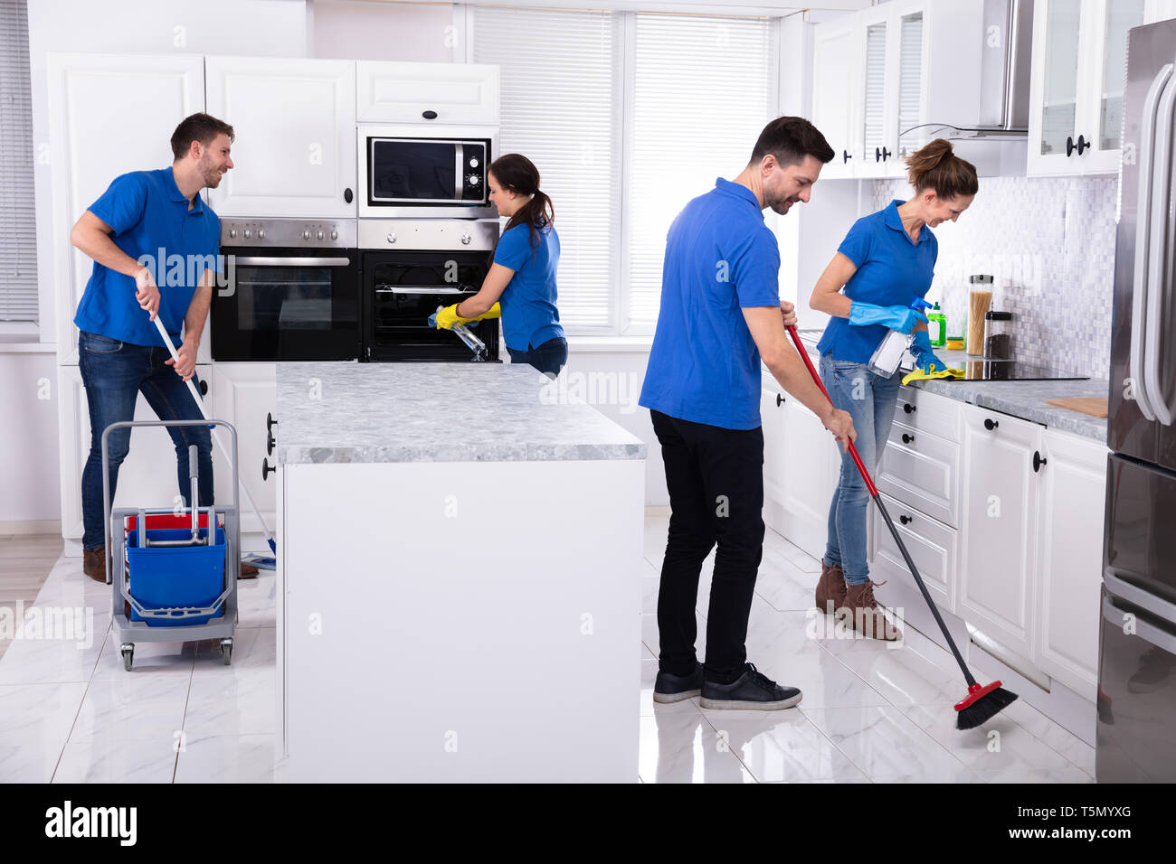 Group Of Young Janitors In Uniform Cleaning Kitchen At Home Stock Photo ...